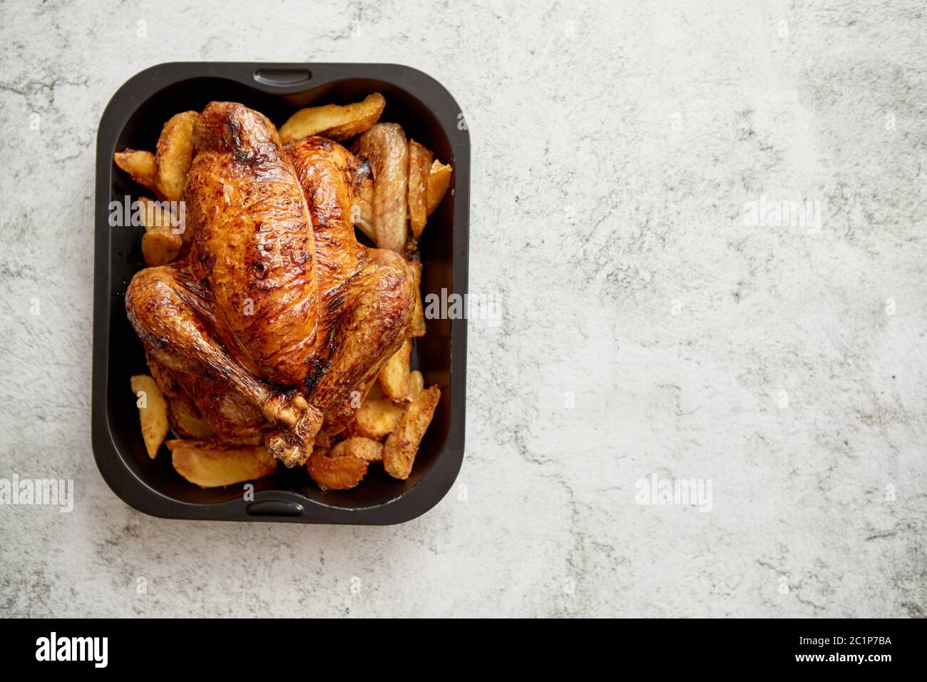 Roasted chicken or turkey with potatoes in black steel mold Stock Photo ...