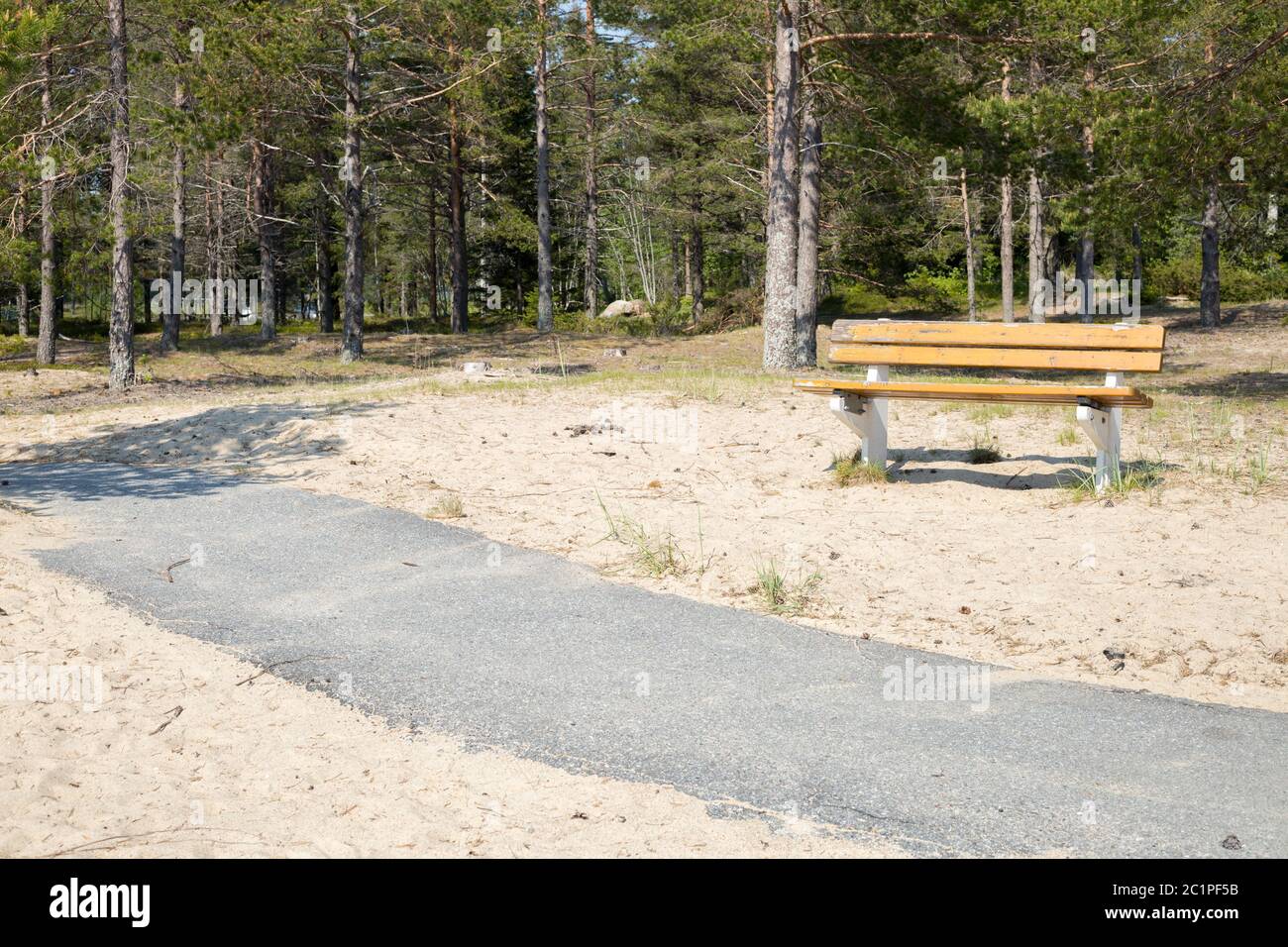 Bench in sand by tarmac walkway Stock Photo - Alamy