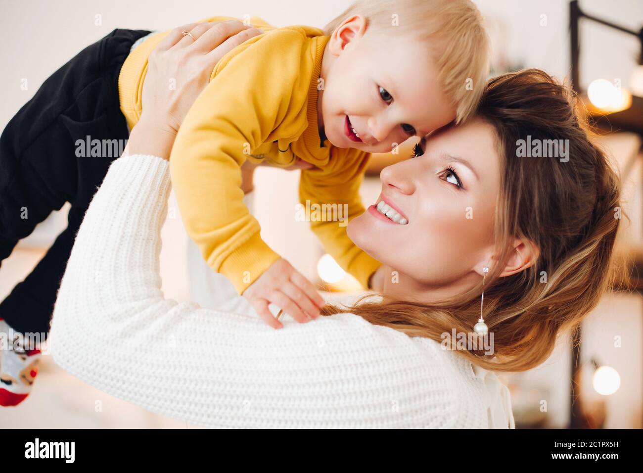 Lovely mother rising up her baby and smiling to each other Stock Photo ...