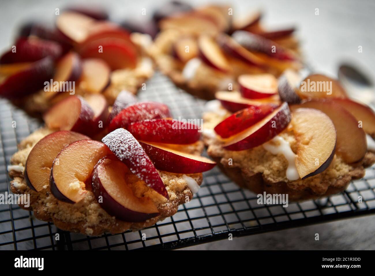 Homemade crumble tarts with fresh plum slices placed on iron baking ...