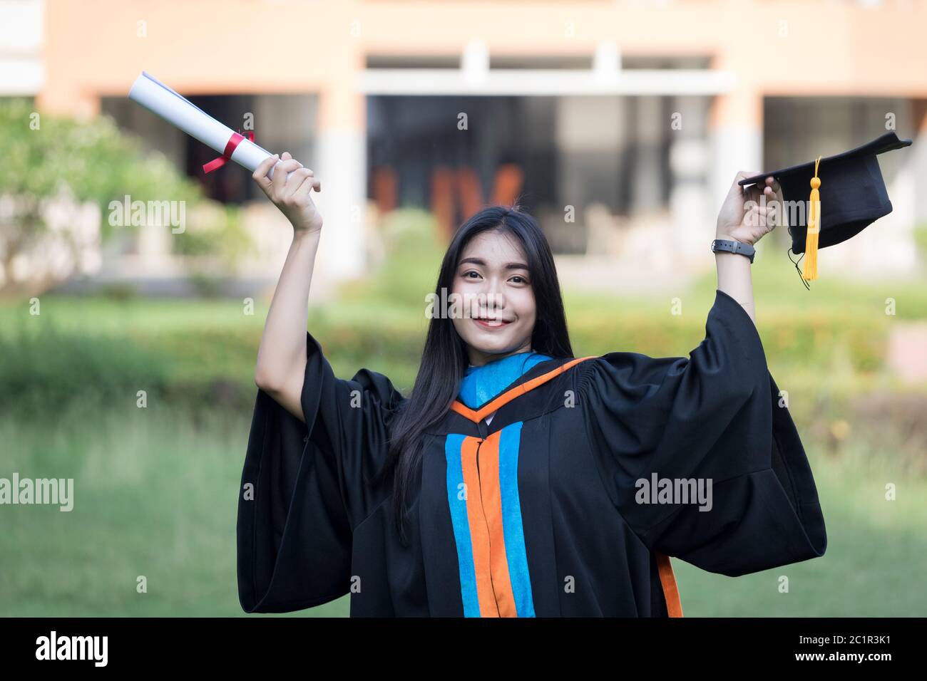 Portrait of a happy and excited young Asian female university graduate ...