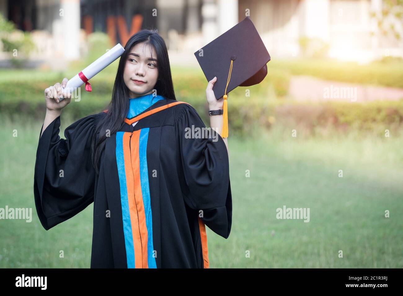 Portrait of a happy and excited young Asian female university graduate ...