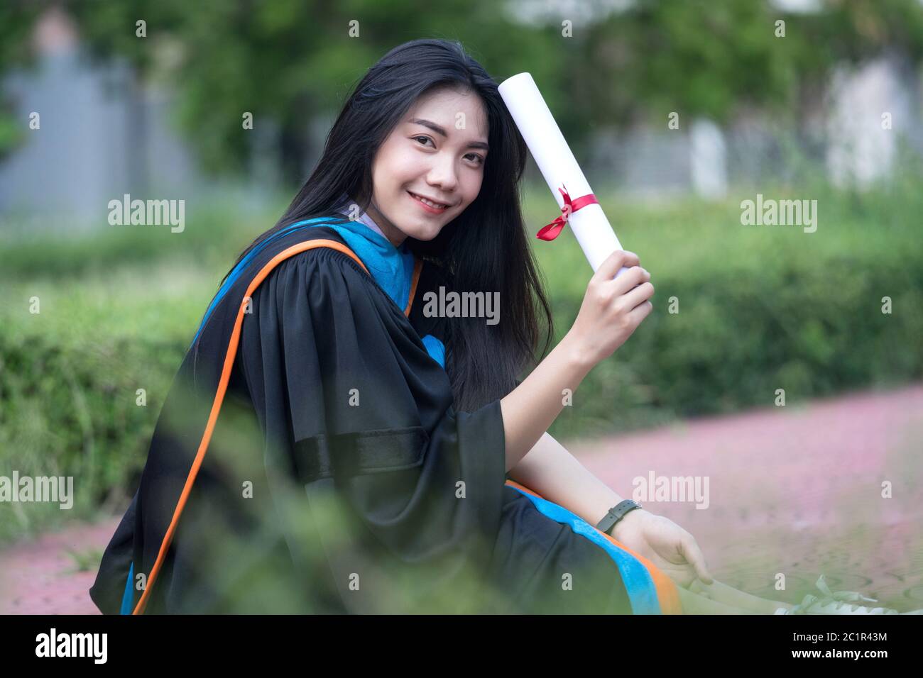 Portrait of a happy and excited young Asian female university graduate ...
