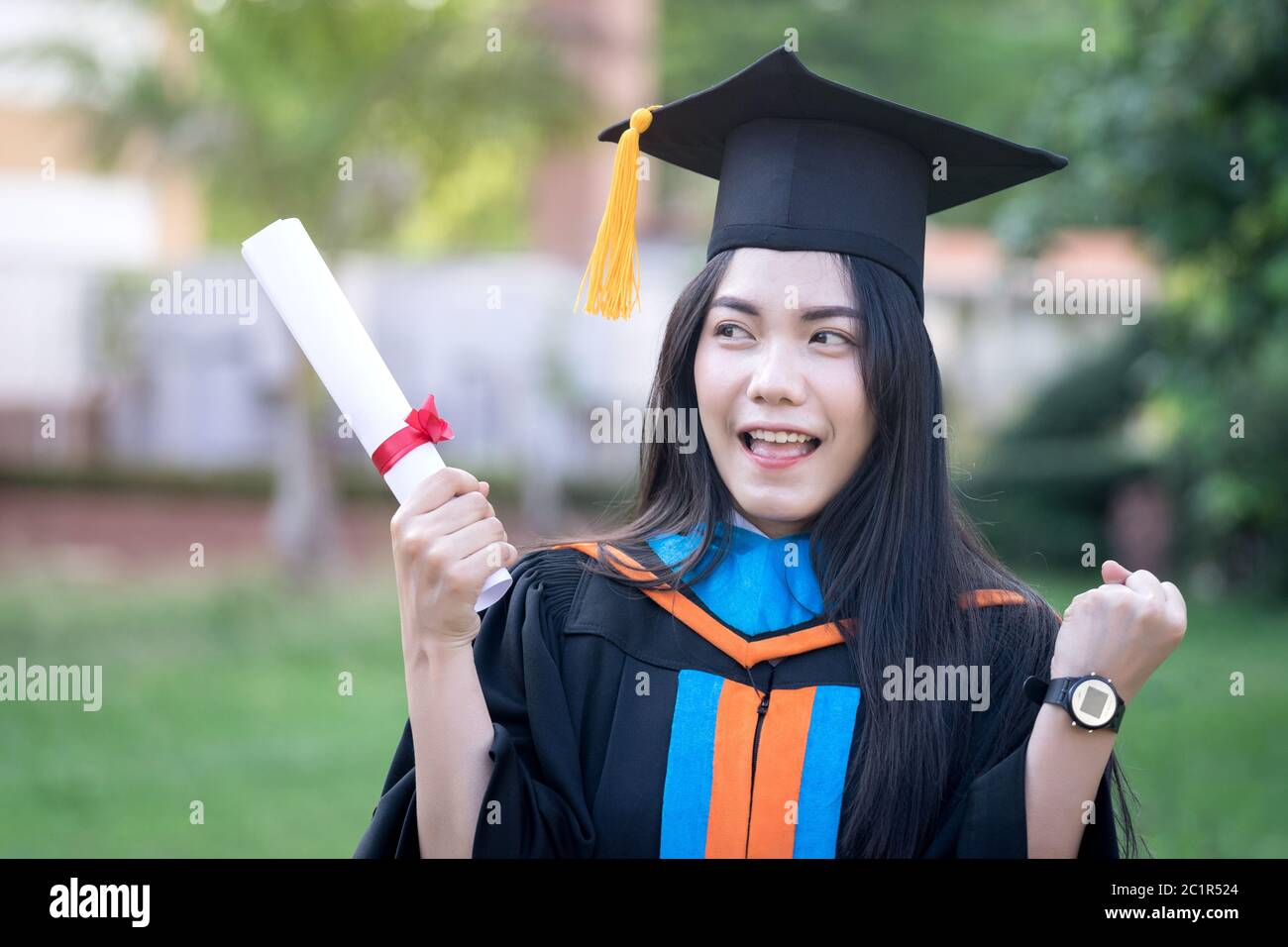Portrait of a happy and excited young Asian female university graduate ...