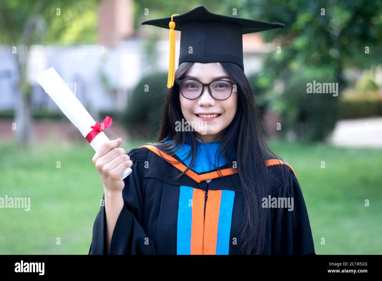 Portrait of a happy and excited young Asian female university graduate ...