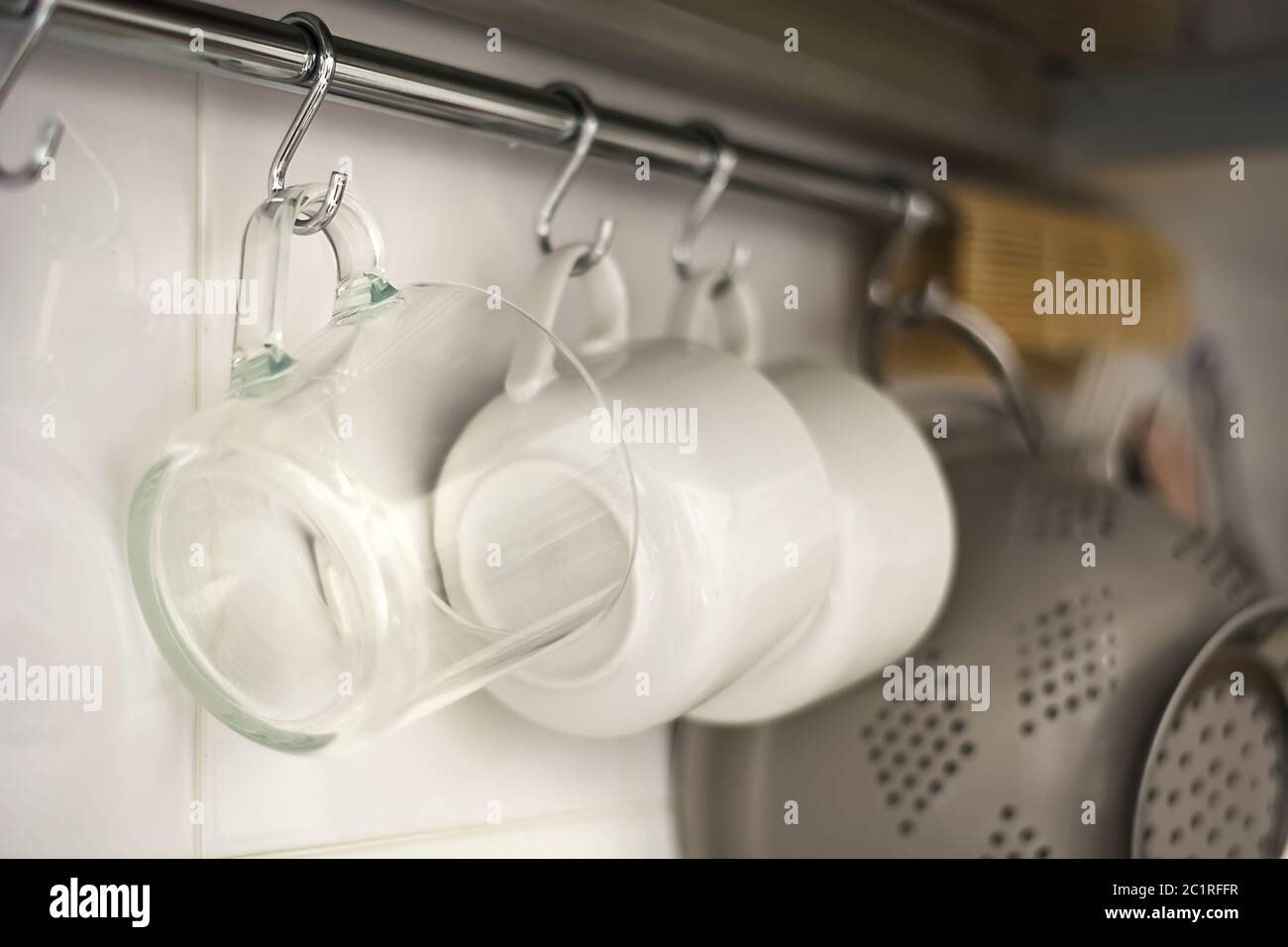 three cups and a colander hanging from a hook in a kitchen Stock Photo ...