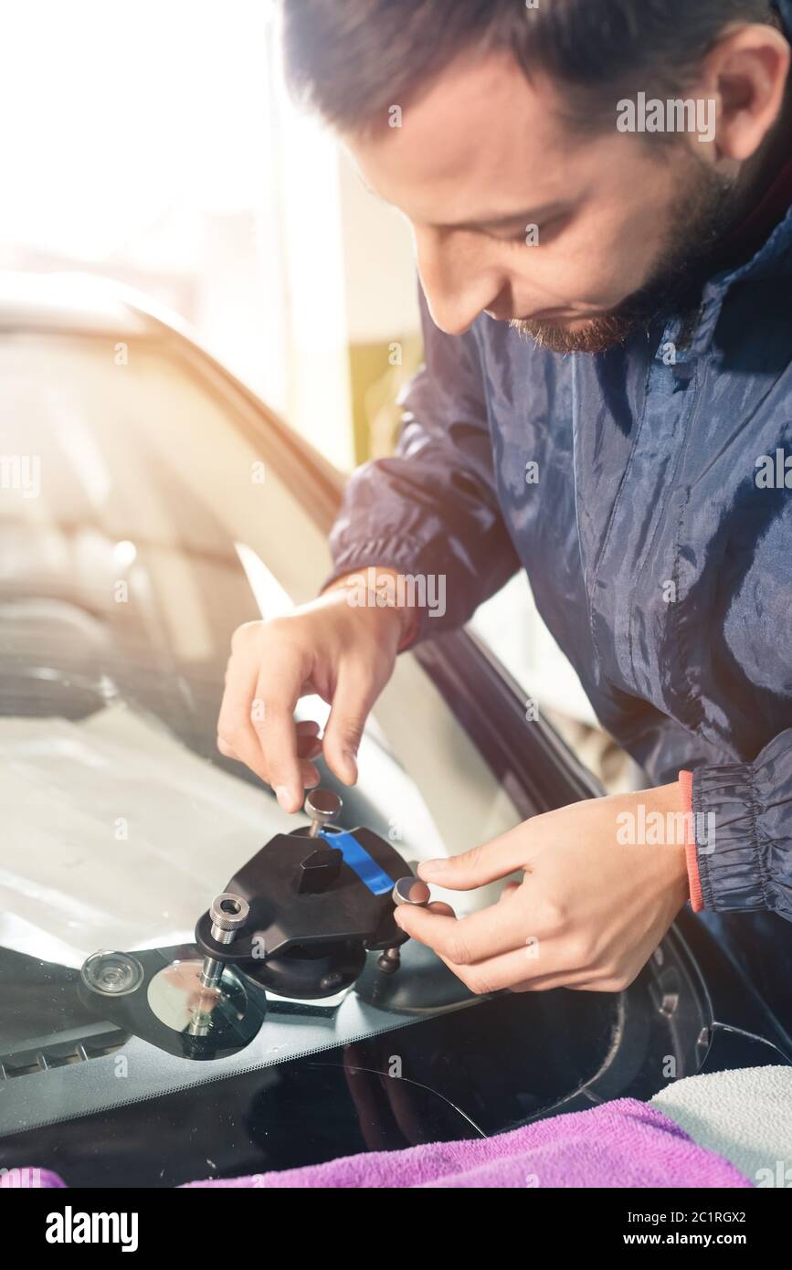 Close-up of a professional windshield repairman working with hydraulic ...