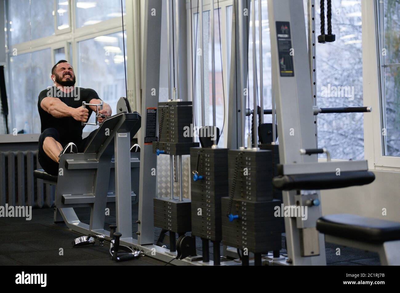strong young man pulling heavy weight sitting in sport fitness ...