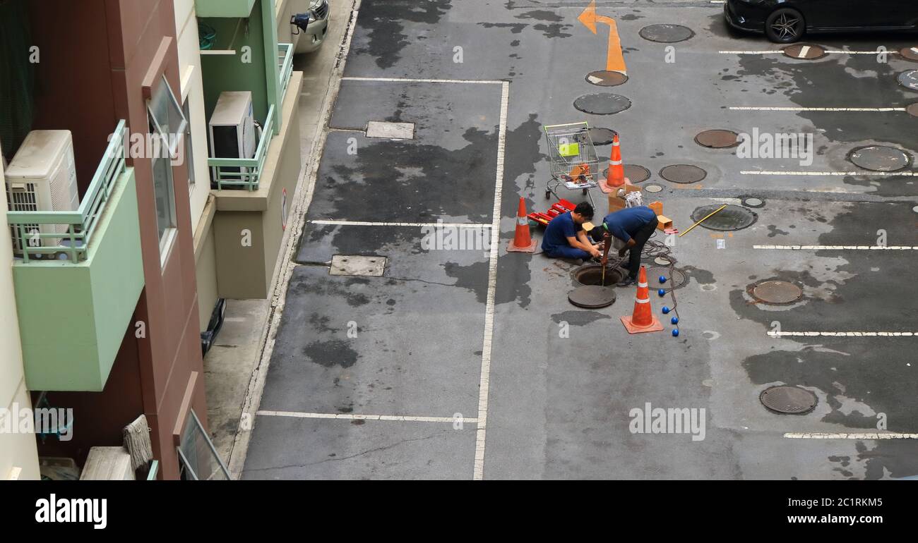 Bangkok, Thailand- June 16, 2020: Two workers working at the manhole to ...