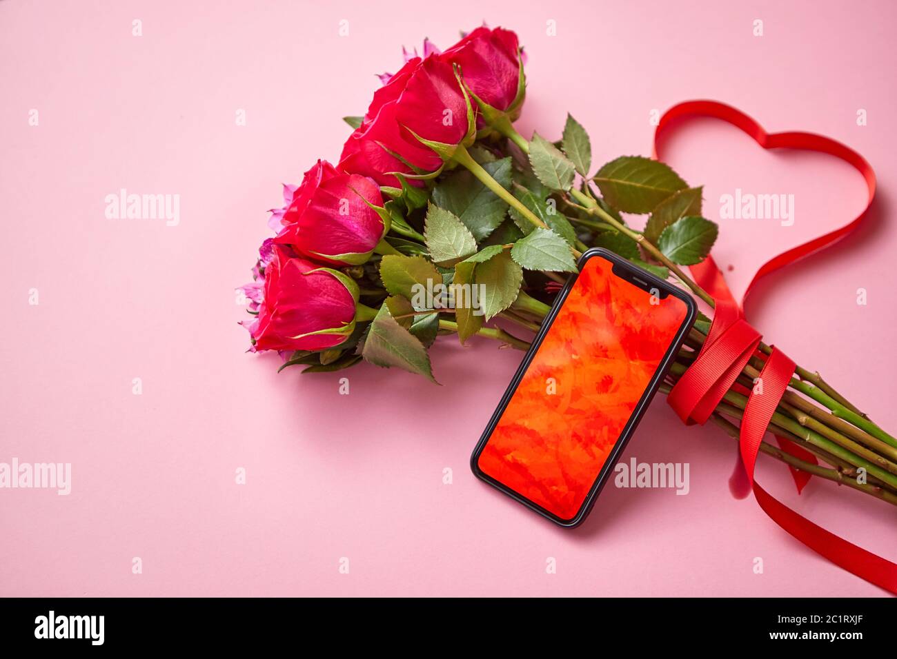 Pink roses bouquet with hart shaped bow and mobile phone with copy ...
