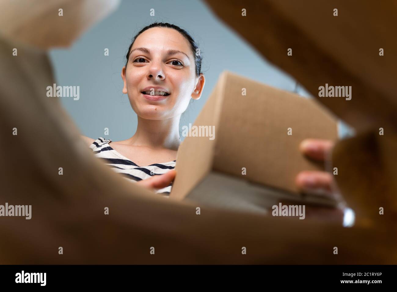 Caucasian woman opens craft paper delivery package with happy emotion ...
