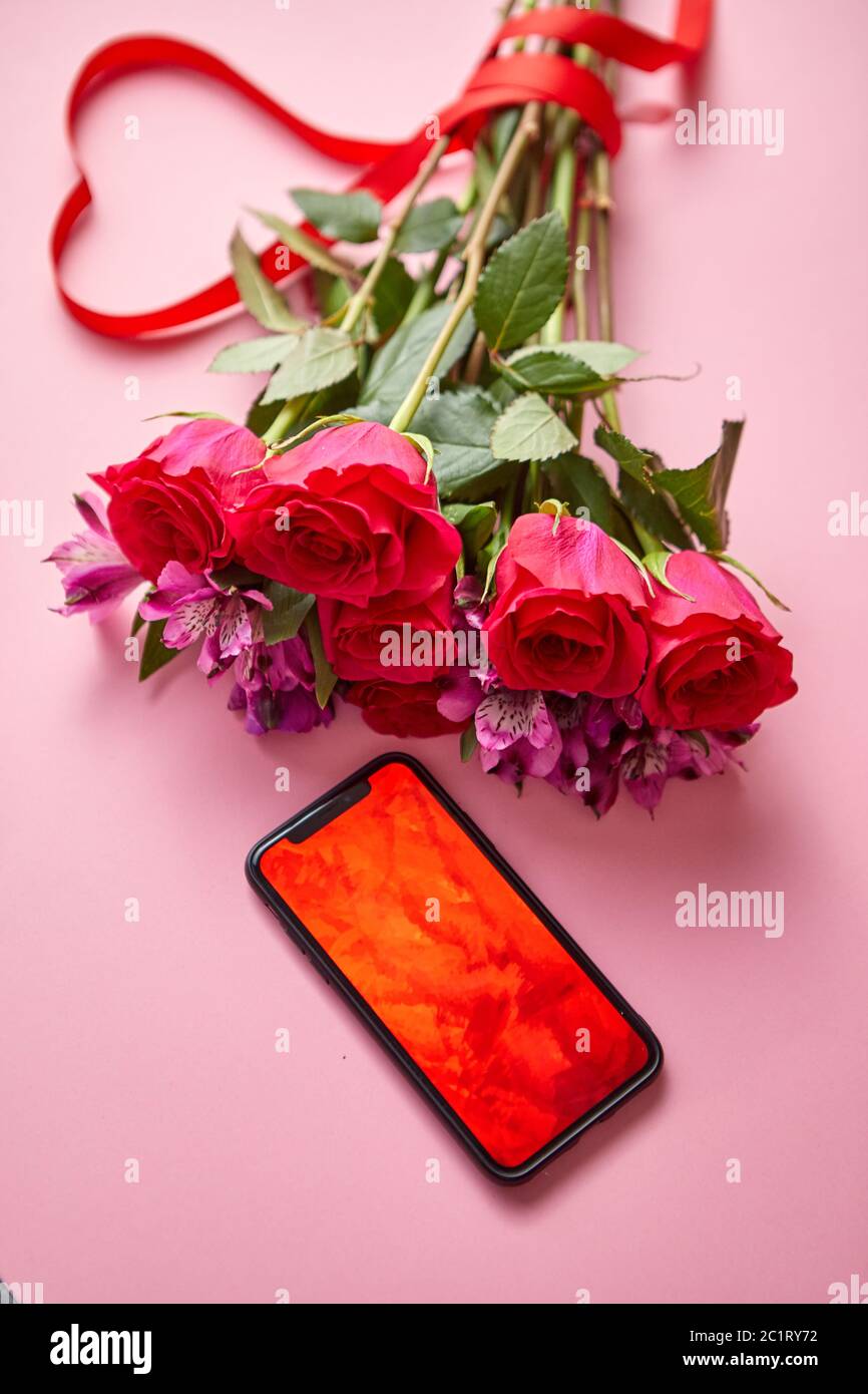 Pink roses bouquet with hart shaped bow and mobile phone with copy ...