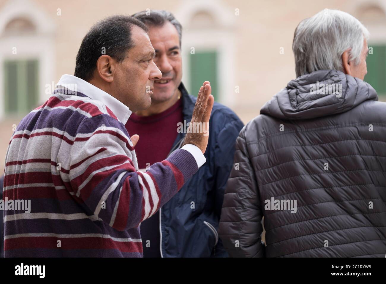 Three Italian men talk and gestuurd to each other on the square Piazza ...