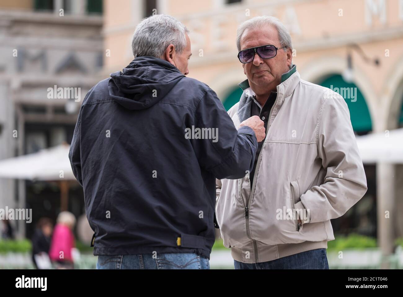 TwoItalian men talk and gesture to each other on the square Piazza del ...