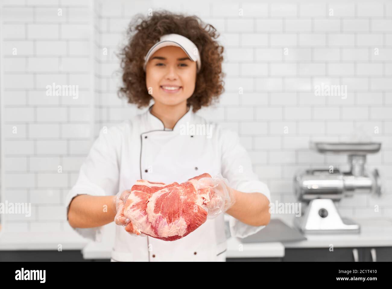 Selective focus of fresh red raw meat in hands of young smiling woman ...