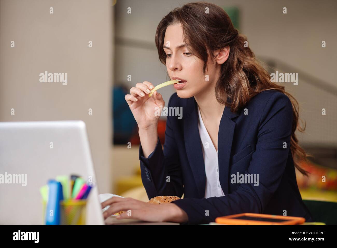 Woman at a laptop eating and working Stock Photo - Alamy