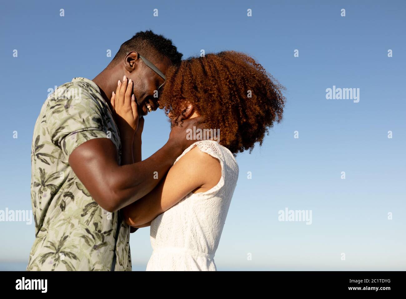 Mixed race couple holding cheeks on the beach Stock Photo - Alamy