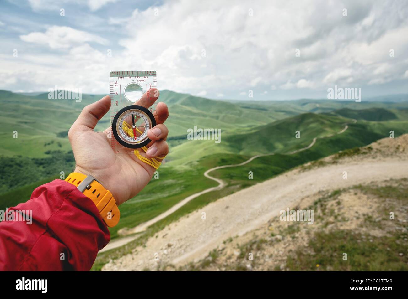 Male hand is holding a magnetic compass on the background of hills and ...