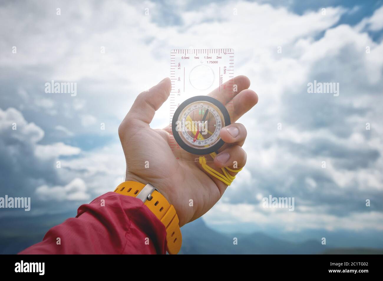 Male hand is holding a magnetic compass on the background of sky with ...