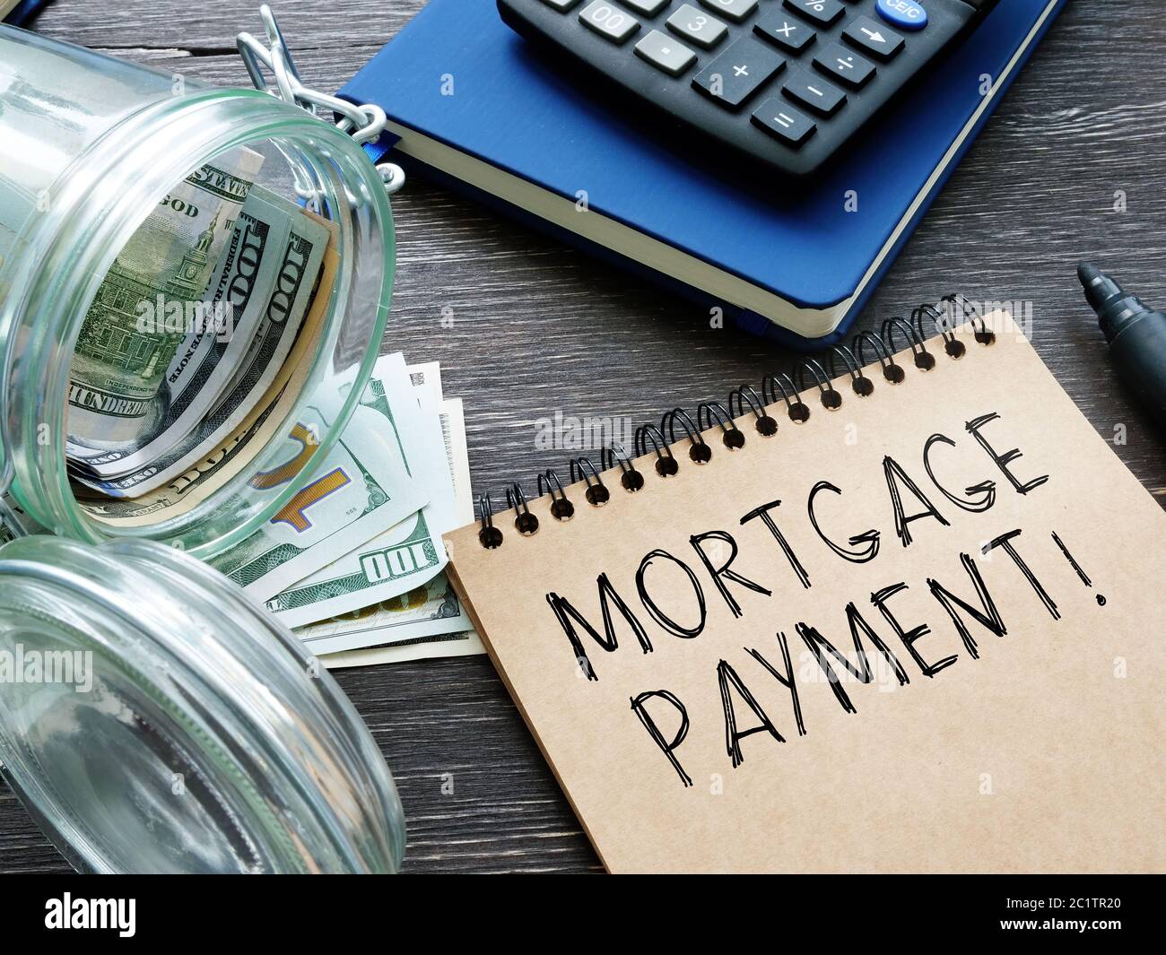 A reminder Mortgage payment written in a notebook. Calculator and jar ...