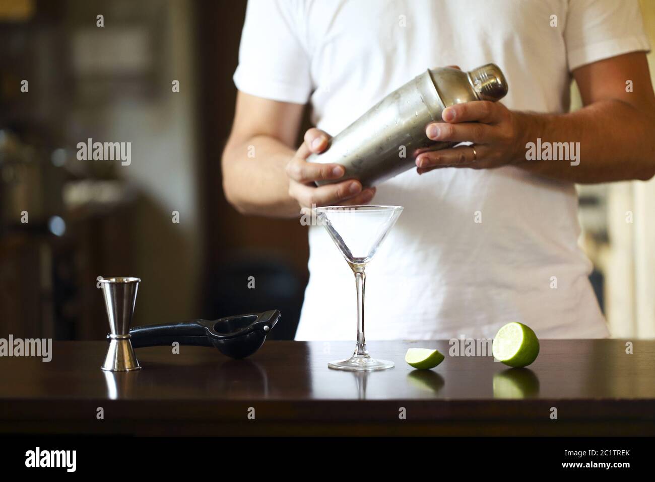 Barman at work, preparing cocktails. Pouring martini to cocktail glass ...