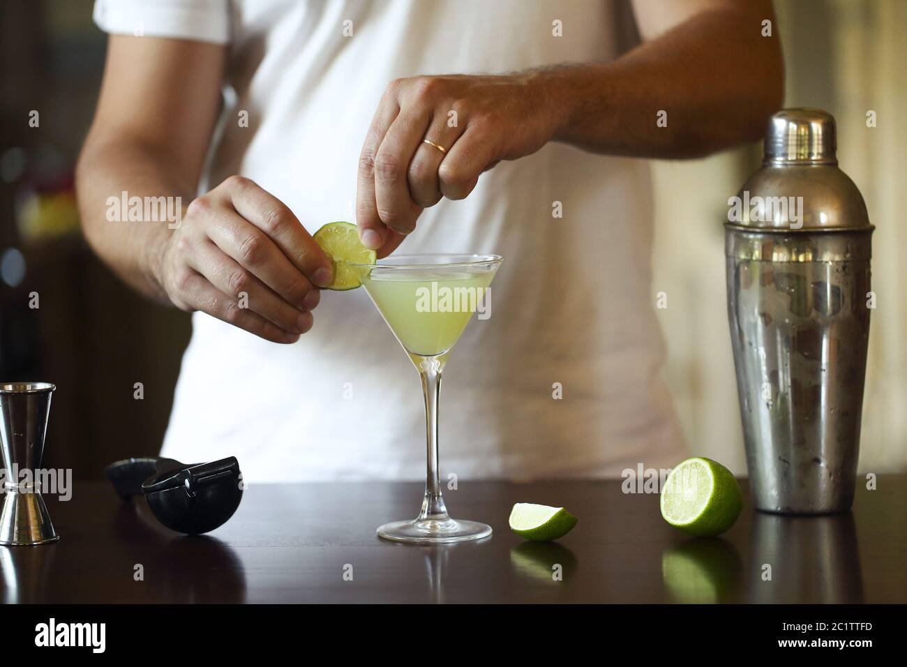 Barman at work, preparing cocktails. Pouring martini to cocktail glass ...