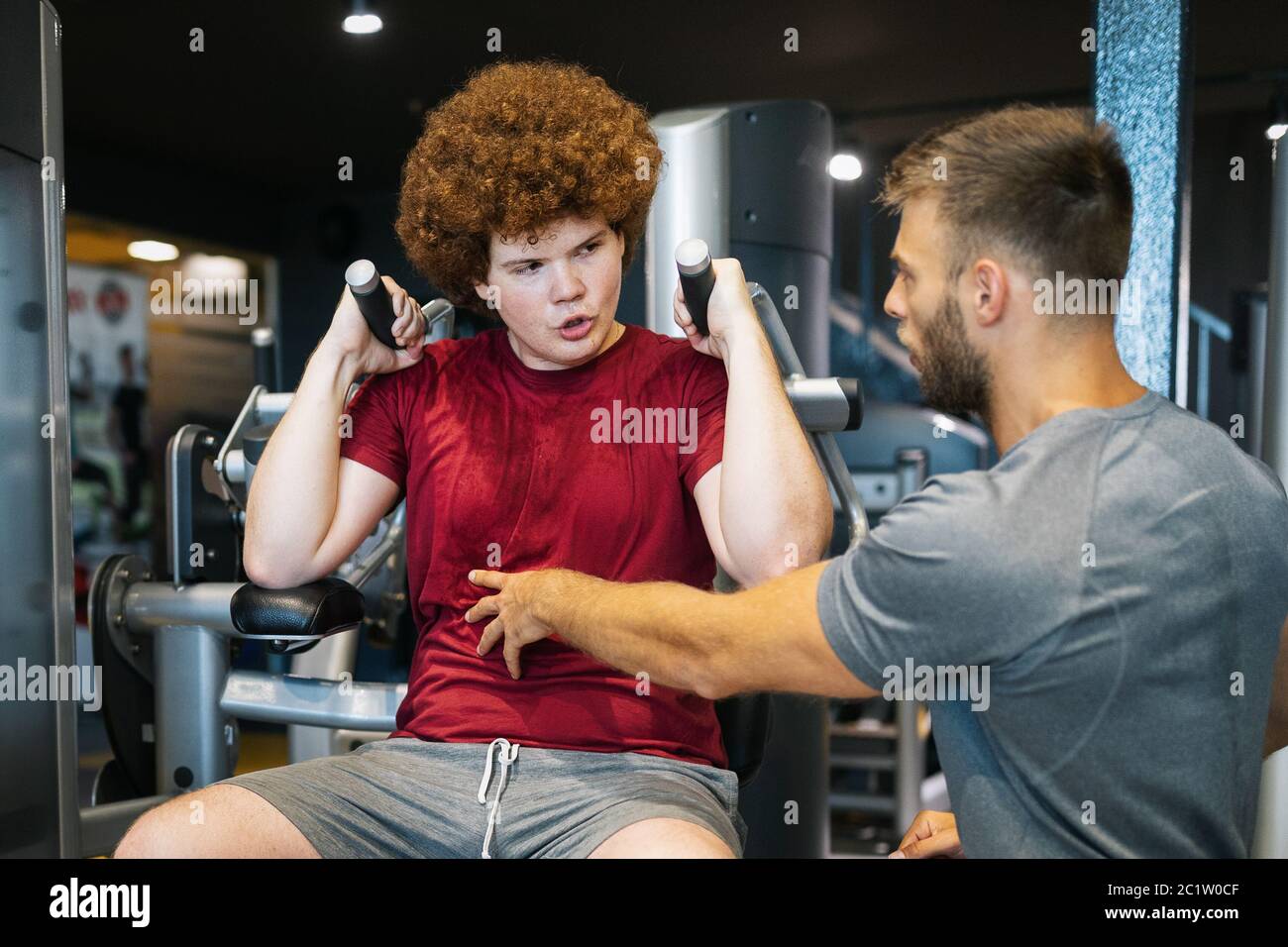 Overweight young man exercising gym with personal trainer Stock Photo ...