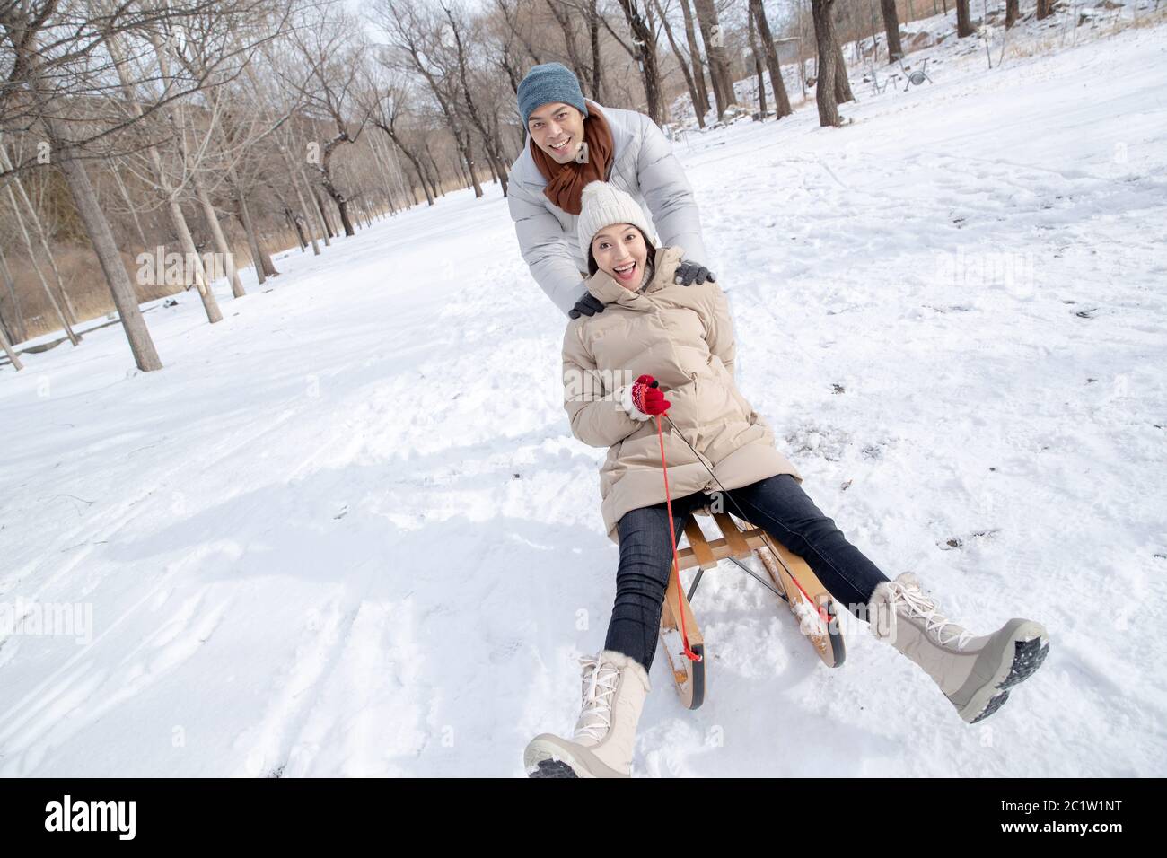 The young couple sledding in the snow Stock Photo - Alamy