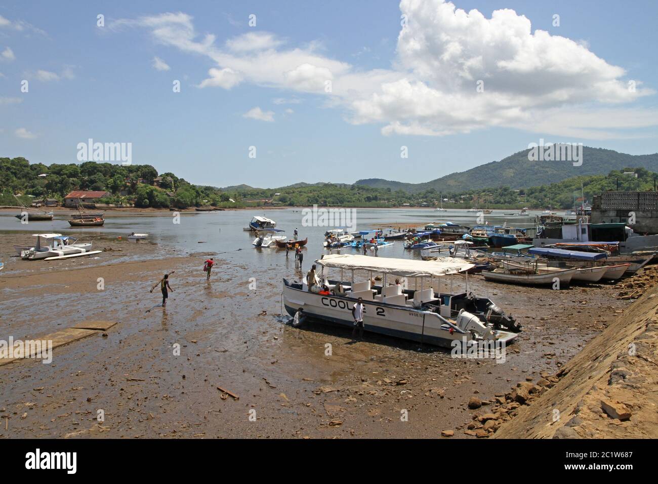 Beached boats and man carrying log in Andoany Harbour or Hell-Ville ...