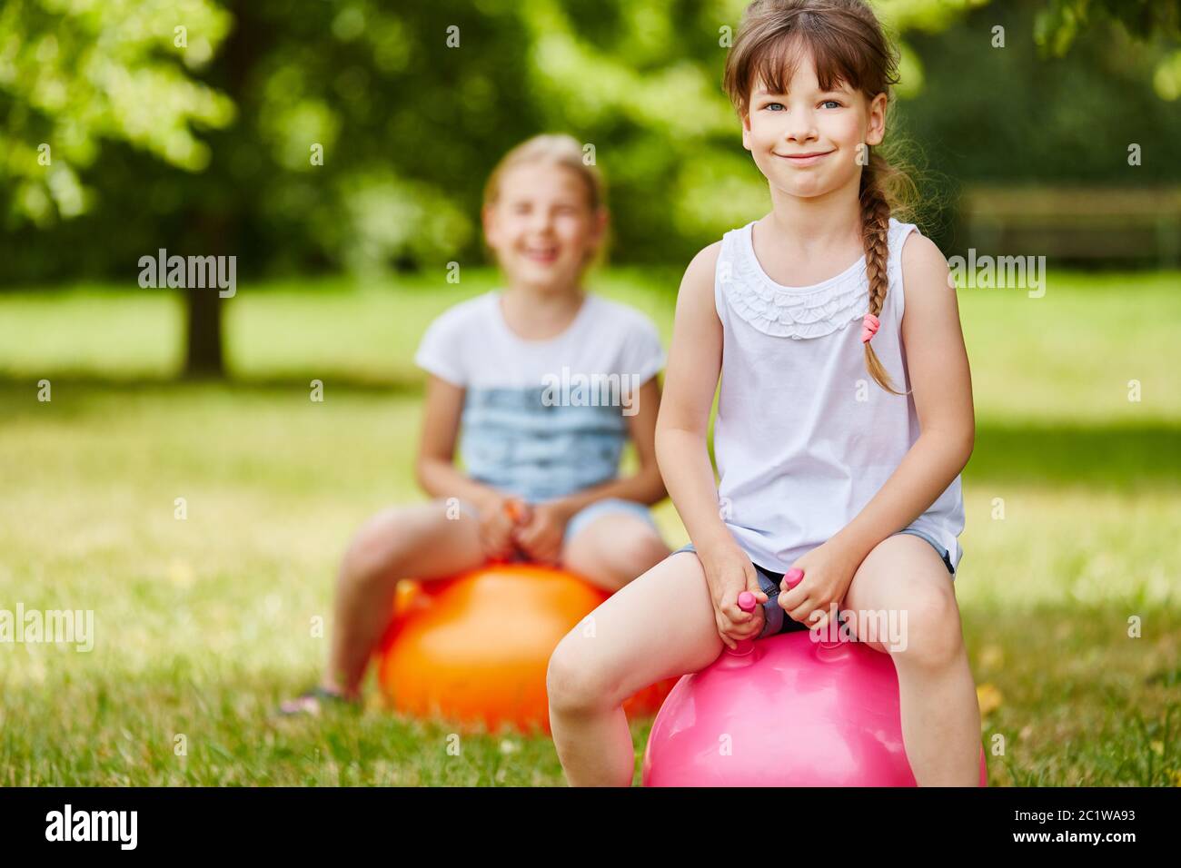 Two girls bounce with bouncy ball in the garden in summer Stock Photo ...