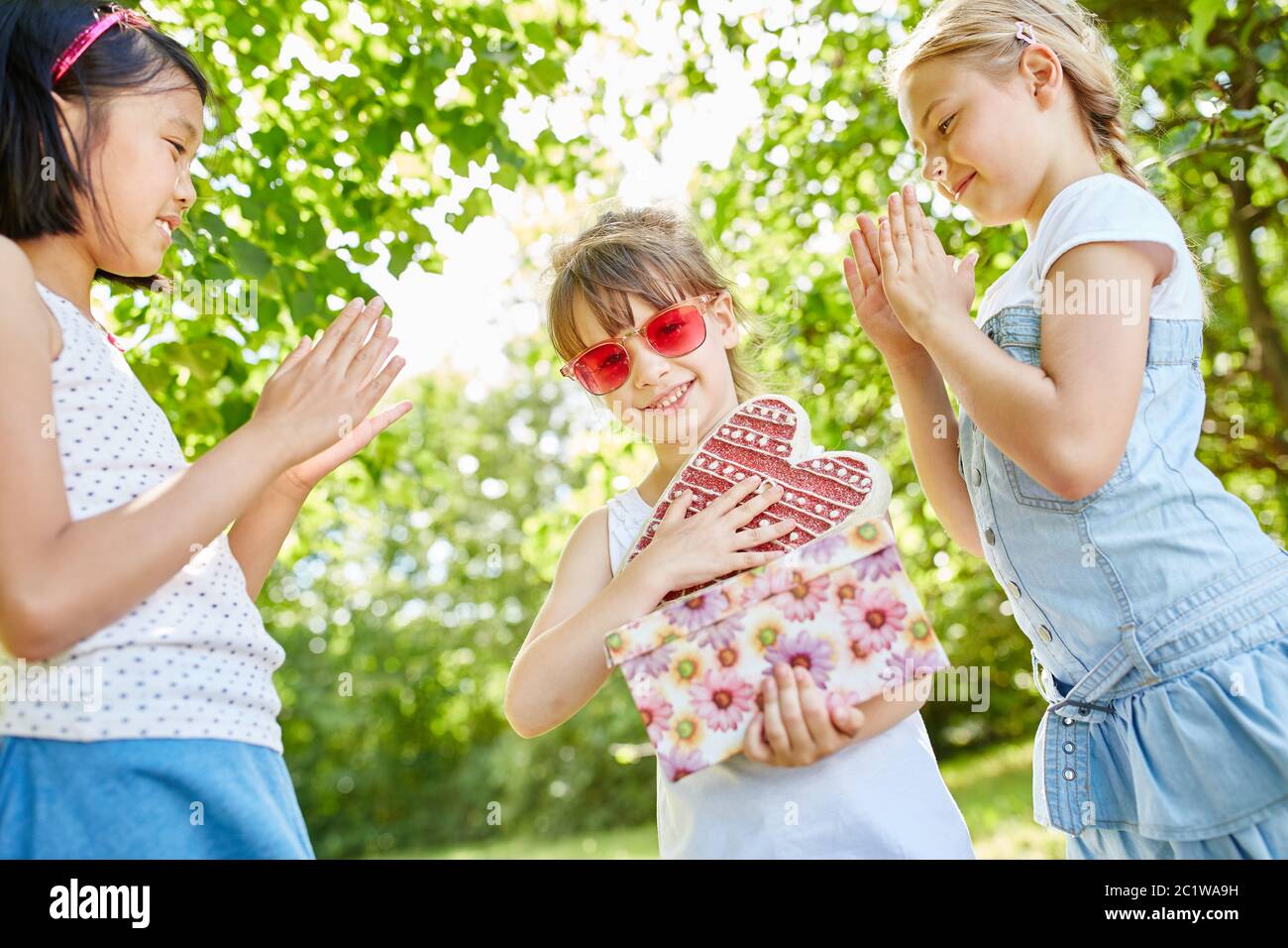 Children congratulate birthday child on birthday with gift and applause ...