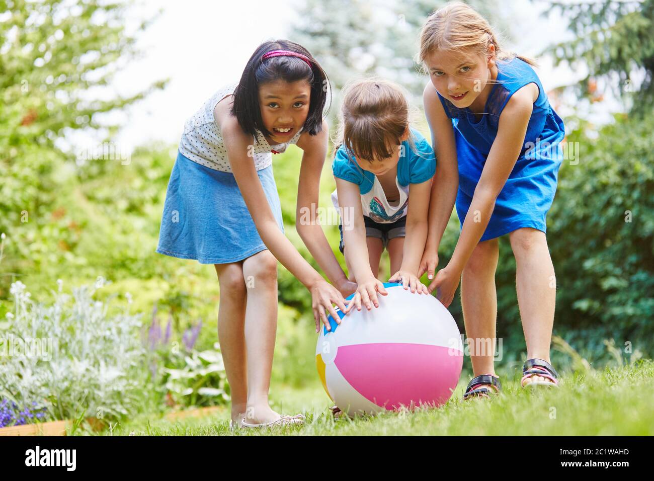 Three happy children play together with a ball in the garden Stock ...