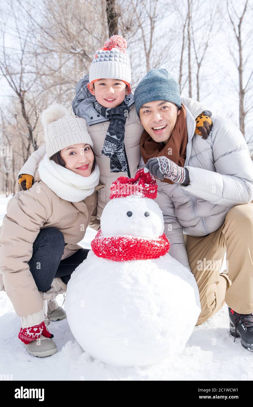 Three make a snowman in the snow Stock Photo - Alamy