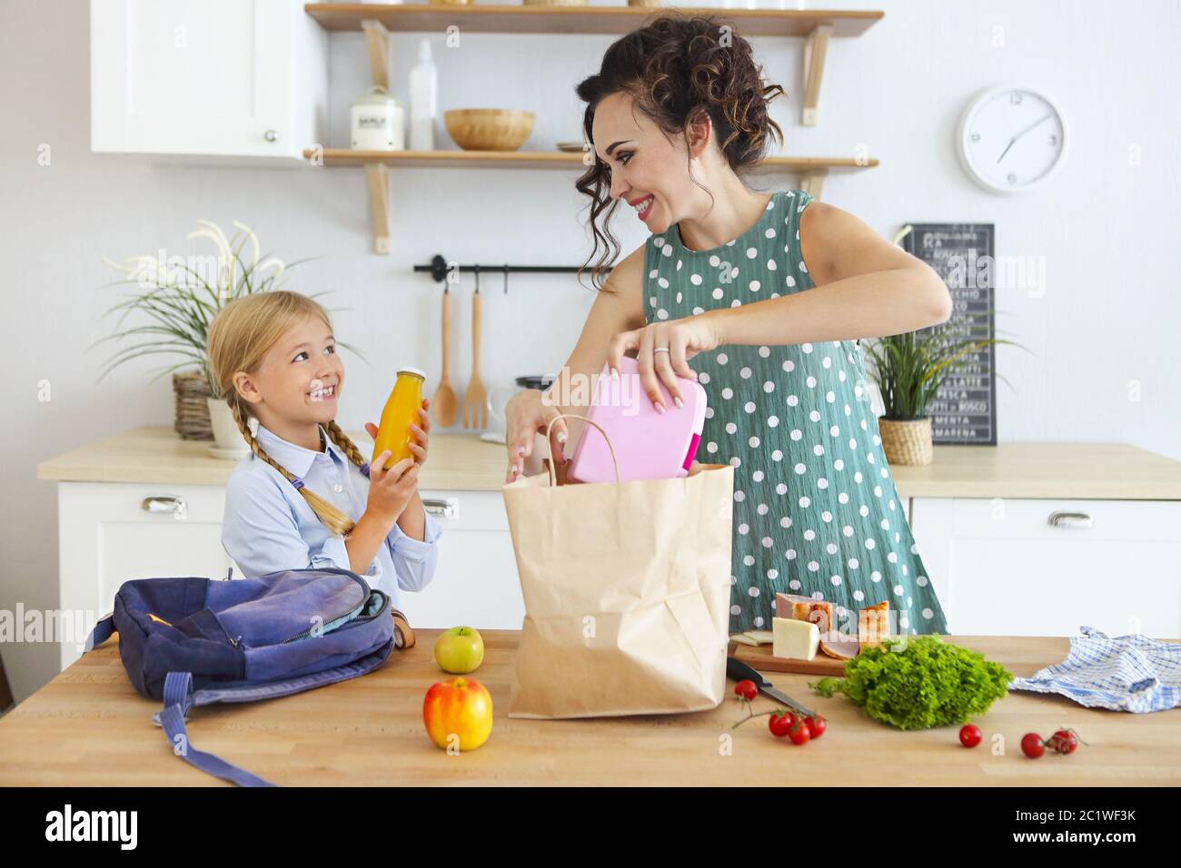 Beautiful brunette mother and her daughter packing healthy lunch and ...
