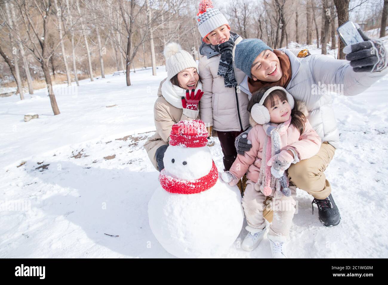 Happy family make a snowman in the snow Stock Photo - Alamy