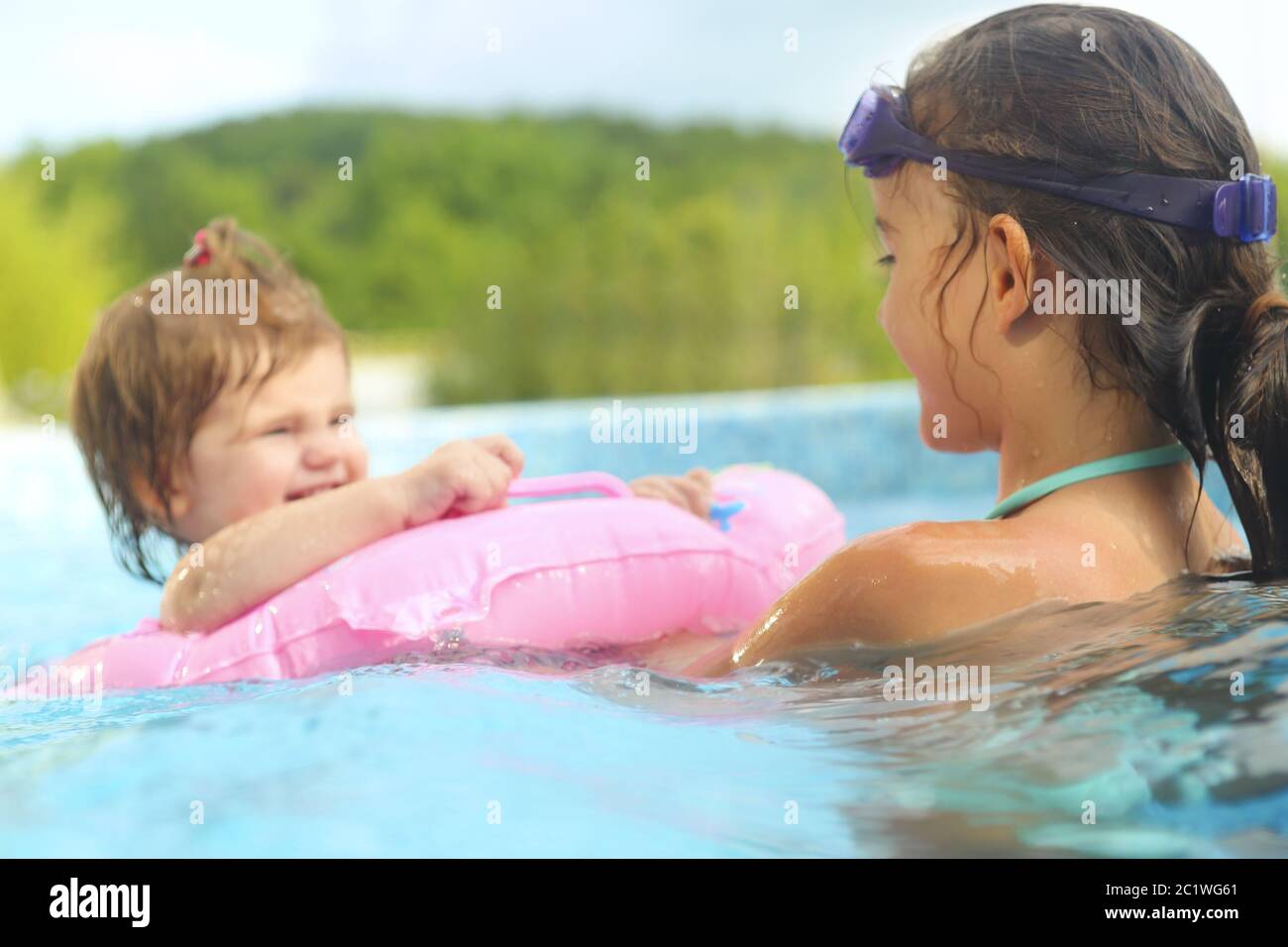 Two cute girls playing in swimming pool Stock Photo - Alamy