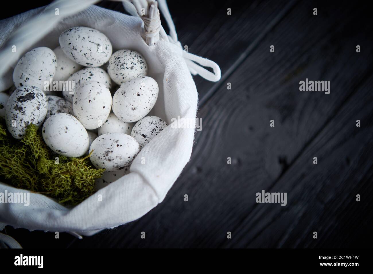 Quail eggs in a nest on a black rustic wooden background. Easter ...
