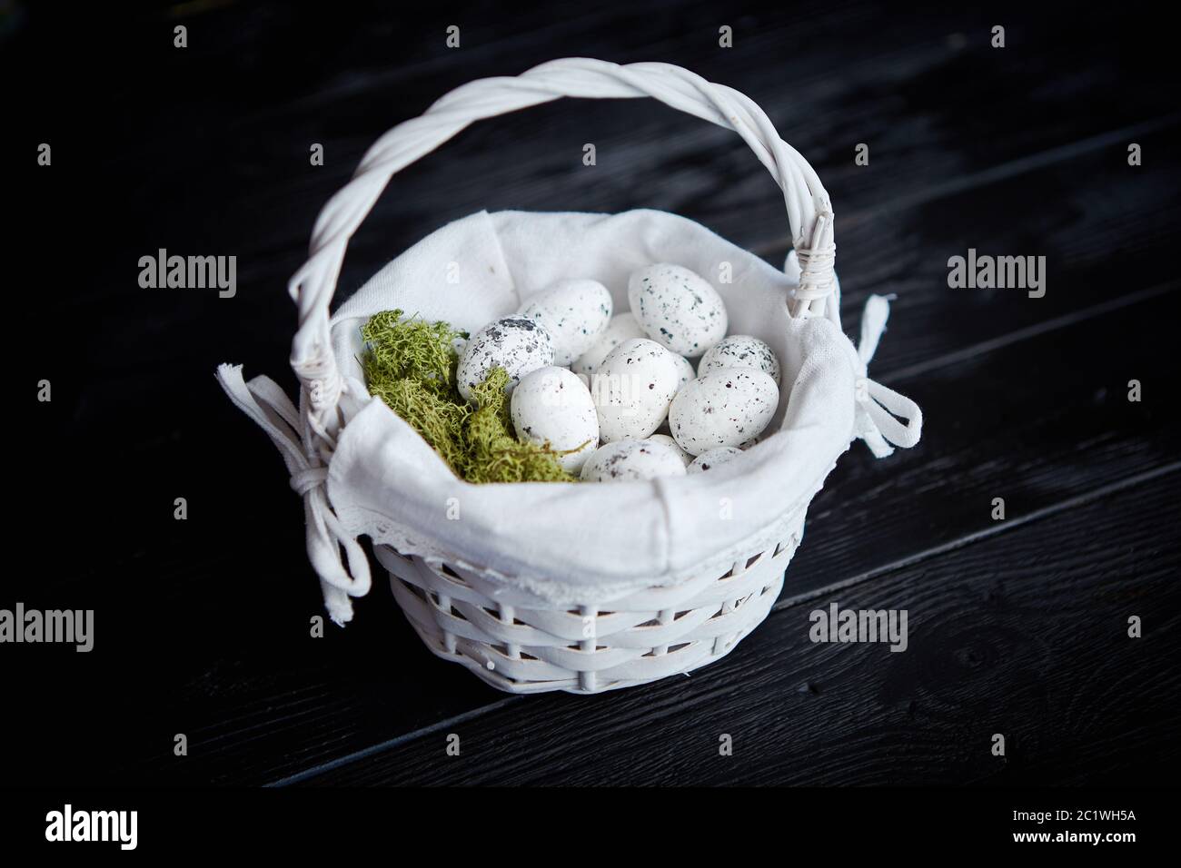 Quail eggs in a nest on a black rustic wooden background. Easter ...