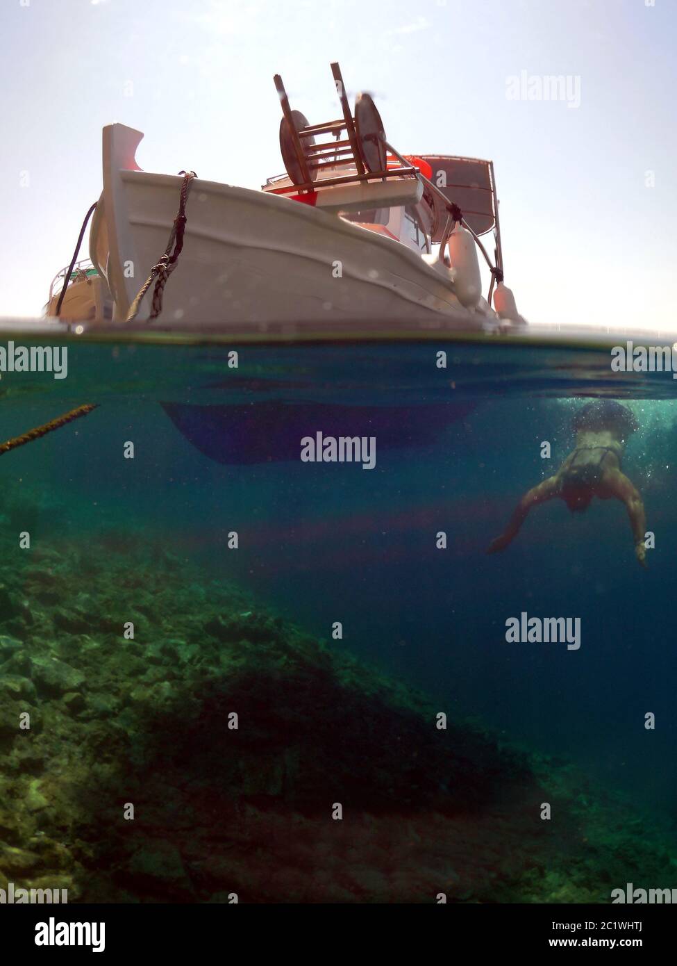 An over and under water of a boat with a woman driving next to it Stock ...