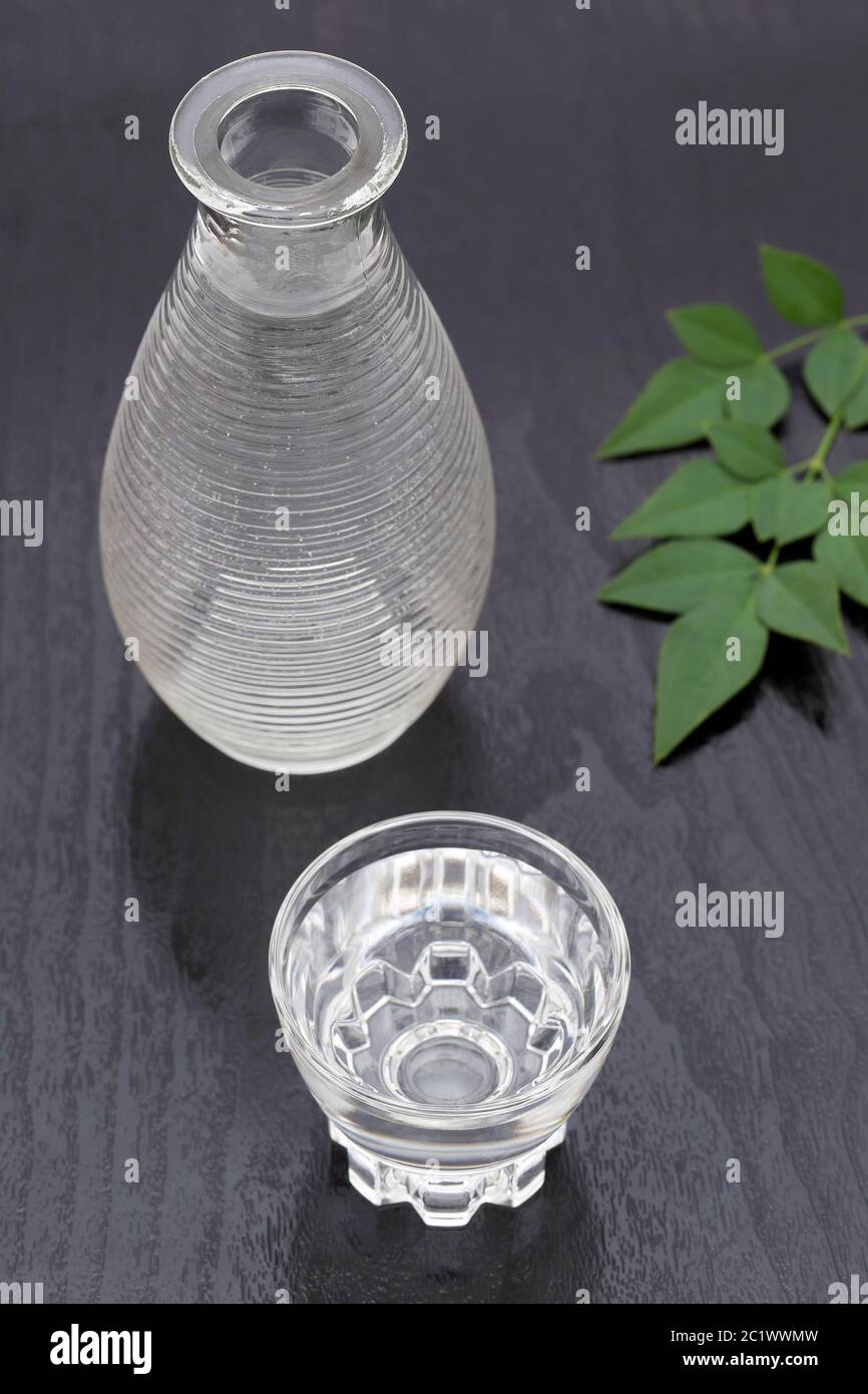Japanese sake in transparent glass cup and jar on black background ...