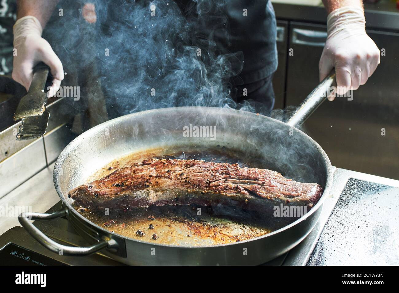 The chef works in the kitchen of the restaurant. Fresh meat roasted in ...
