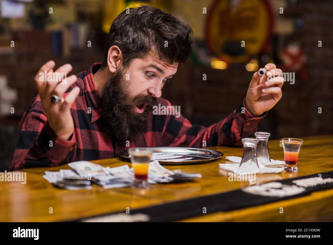 Hipster with beard sniffs cocaine, drug. Man with shocked face looking ...