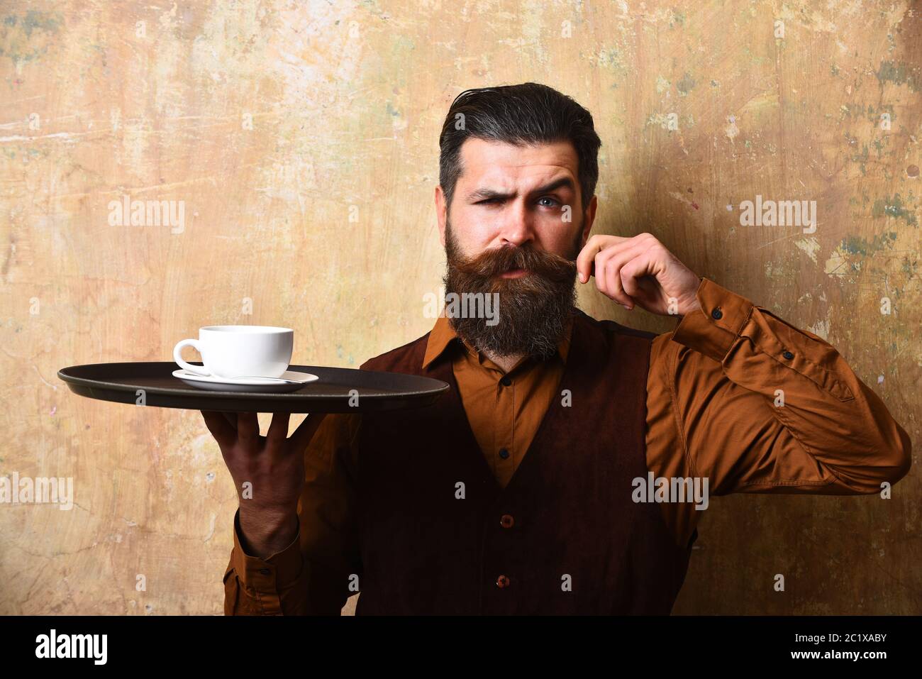 Waiter with white tea cup on tray. Man with beard curls mustache ...