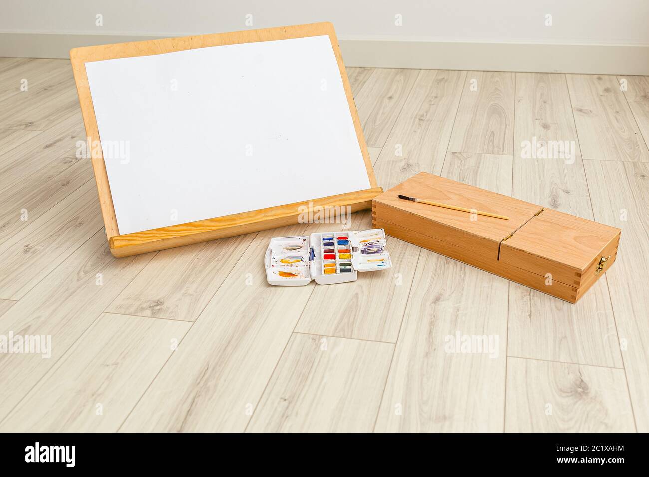 Wooden easel and sheet of paper with watercolor paint. Contented ...