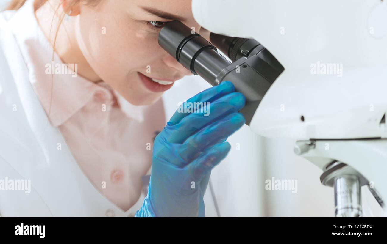 close up. female scientist looking through a microscope Stock Photo - Alamy