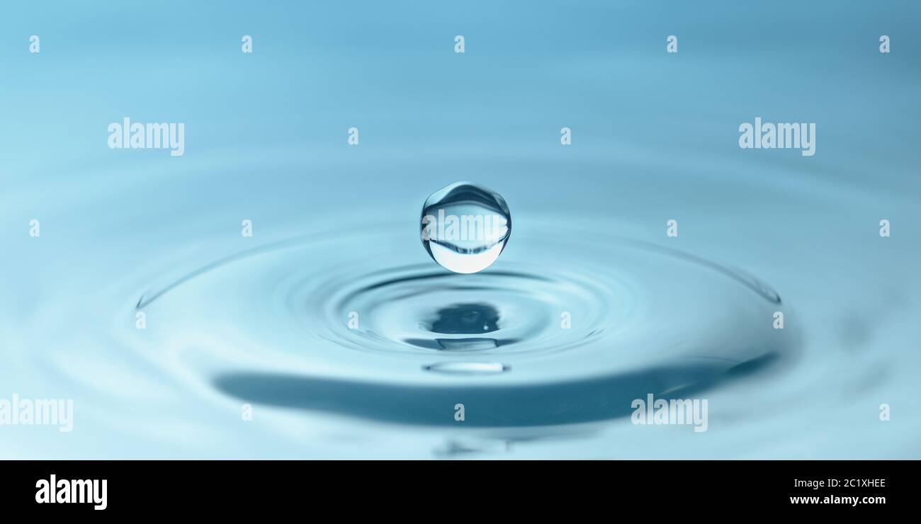 a drop of water drips into the blue water, forming ripples, close-up ...