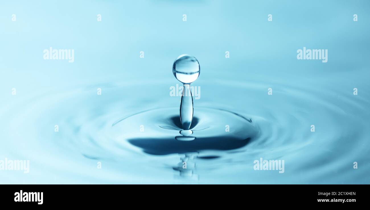 a drop of water drips into the blue water, forming ripples, close-up ...