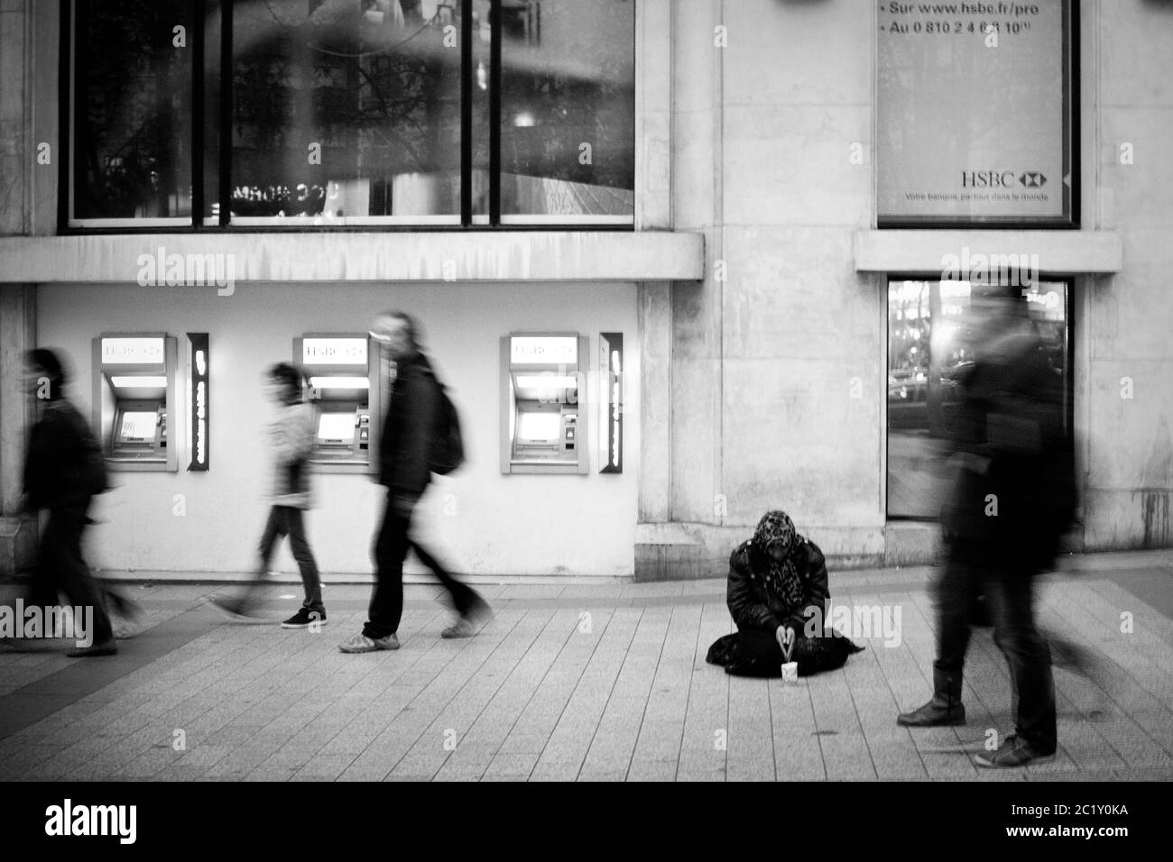 A homeless person begging on the street while people walk by Stock ...