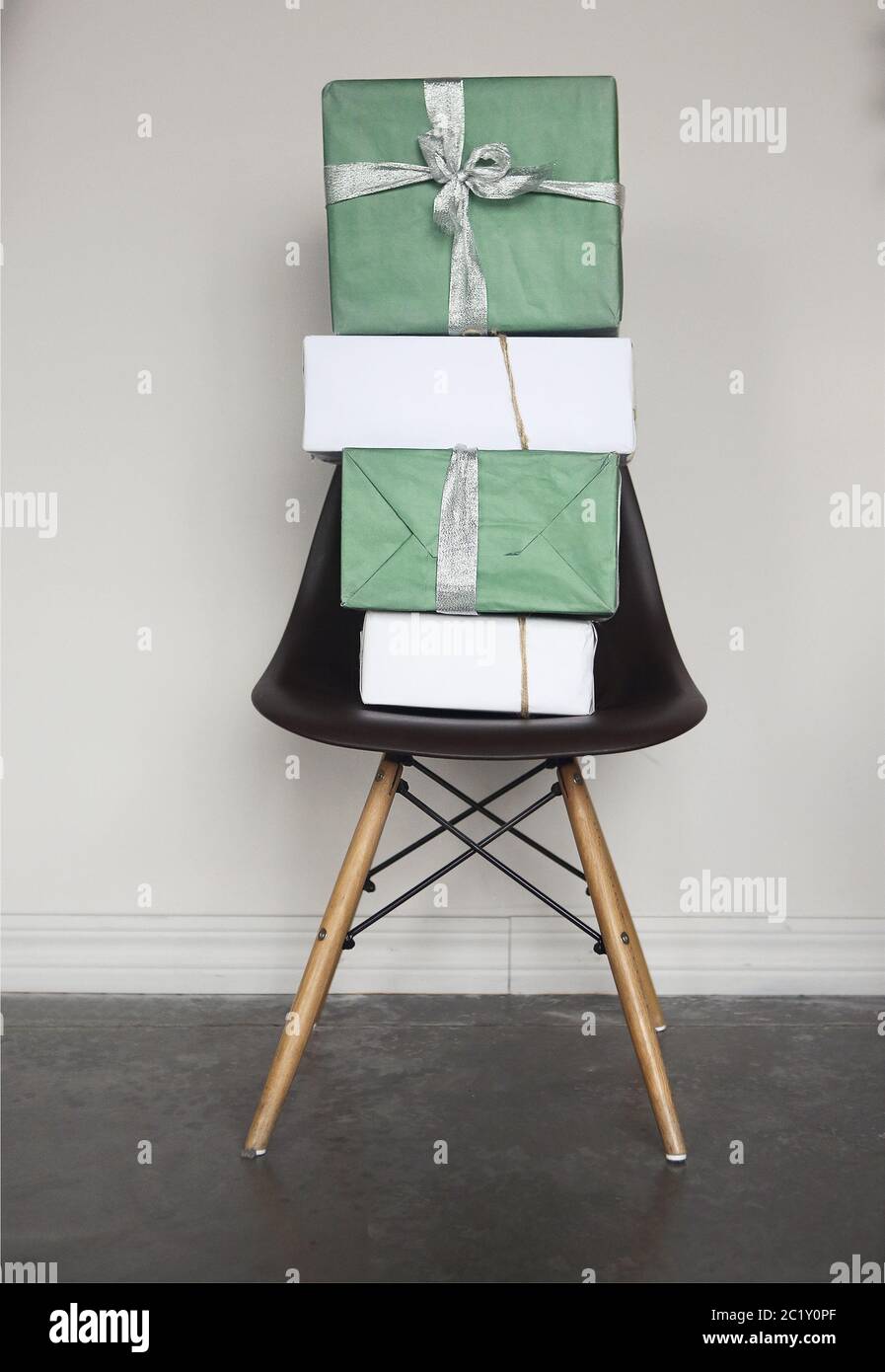 Green and white Christmas gift boxes with red ribbons on chair near ...