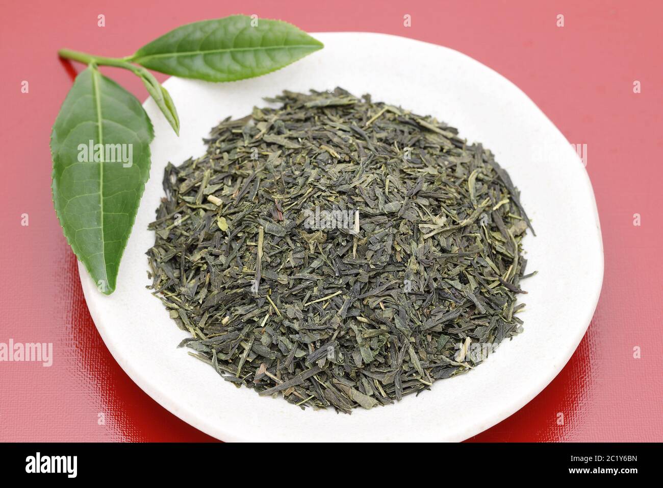 dried tea leaves with green tea leaves on red background Stock Photo ...